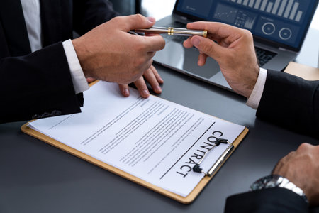 Two businesspeople sit across the desk as business deal is taking place ...