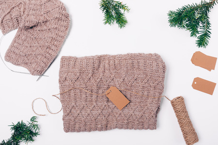 Handmade wool sweater lies on white table amidst flat lay frame of fir ...