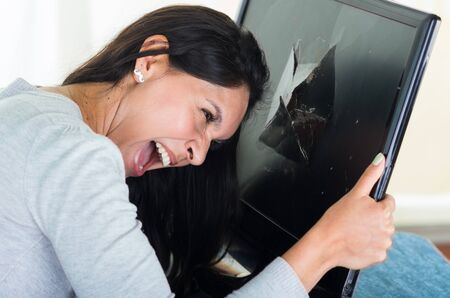 Brunette hispanic model holding up broken black computer screen while ...