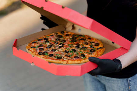 Pizza with salami and cheese in cardboard box. Safety delivery in black ...