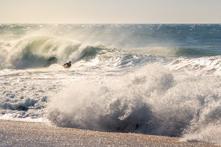 man surfing between powerful waves that break with force next to the ...