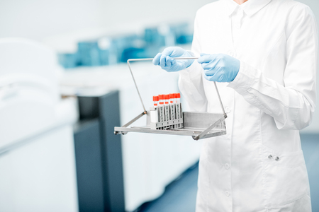 Laboratory assistant holding test tubes near the analyzer machine ...