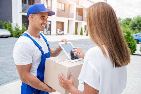 Young courier delivering goods to a young woman at home - Stock Image ...