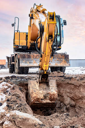 Powerful excavator digs a foundation pit for the construction of a ...