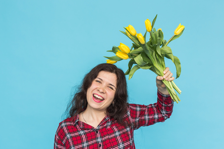 Laughing young caucasian woman with bouquet of tulips on blue ...
