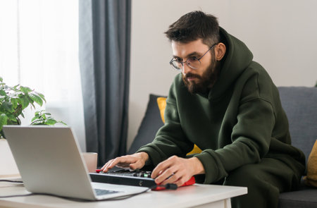 Man recording electronic music track with portable midi keyboard on ...