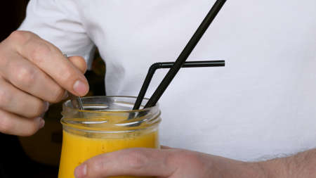 Close-up glass cup with fresh yellow mango smoothie, tasty pulp is ...