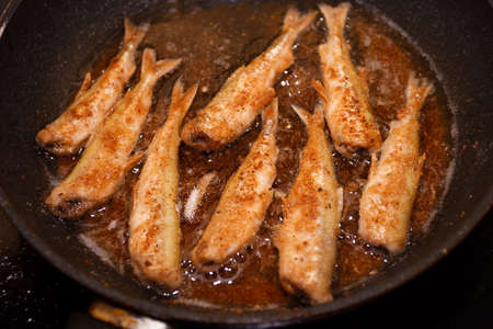 Crispy breaded European smelt fish (Osmerus eperlanus) in a black ...