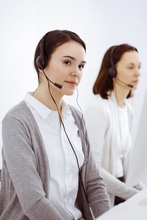 Call center. Casual dressed woman working in headset with diverse ...