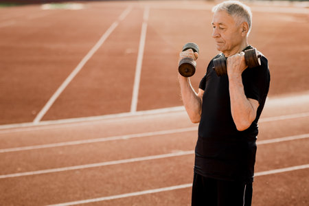 Image of athletic old man in tracksuit doing exercise while working out ...