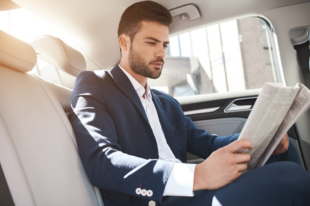 Young stylish businessman reads newspaper on backseat of car - Stock ...