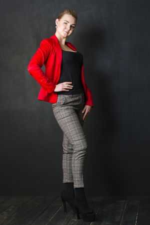 Pretty woman stands in red jacket in black studio, full body - Stock ...
