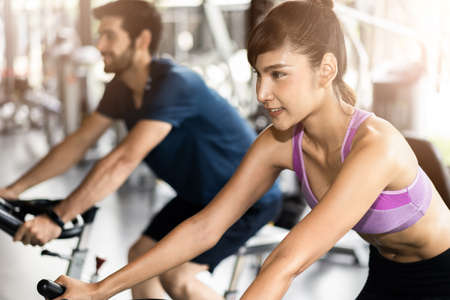 Young fit handsome Caucasian man and beautiful Asian woman cycling on ...