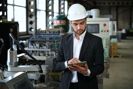 A young plant manager controls the machines process and takes notes on ...