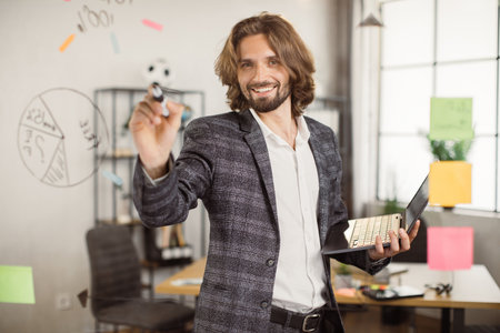 Male office employee with stylish haircut holding modern laptop and ...