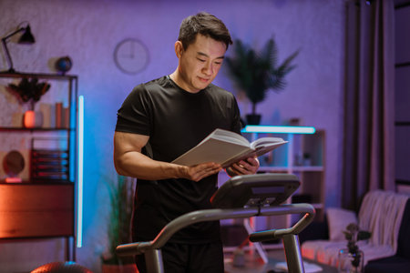 Portrait of active asian man in sportswear reading book while running ...