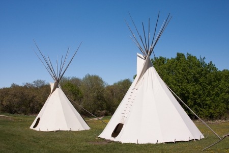 A small group of teepees in a meadow surrounded by forest. Teepees were ...