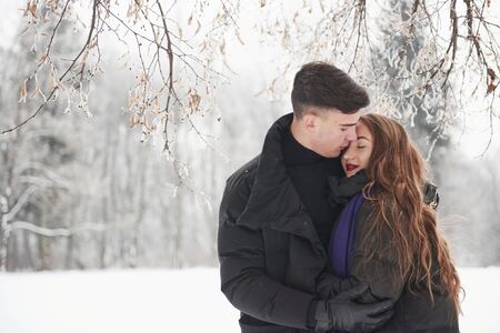 Tree branches in snow. Gorgeous young couple have good time together in ...