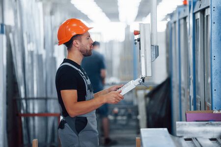 Using machine to program operations. Industrial worker indoors in ...