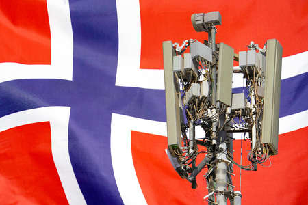 Telecommunications tower with a 5G cellular network antenna agains flag ...