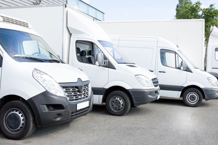 several white row commercial delivery and service van, trucks and car ...