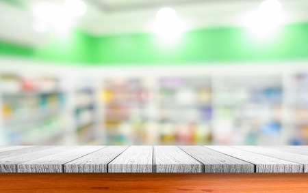 Brown wooden tabletop with blurred pharmacy or medicine shelf at the ...