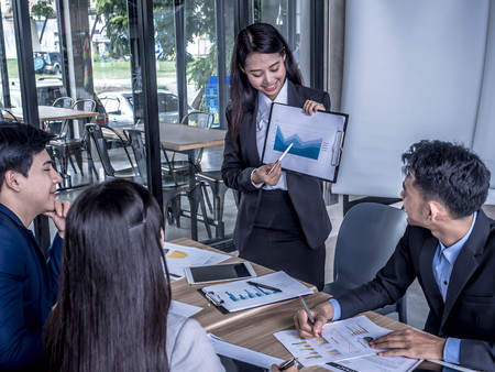 Portrait of beautiful intern standing at office in front of flip chart ...