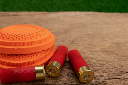 Clay disc flying targets and shotgun bullets on wooden table background ...