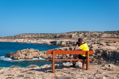 A man on a bench pictures of the Mediterranean Sea. Cape Greco. Cyprusの ...