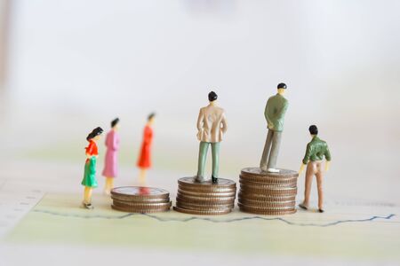 Miniature people: small figures businessmen stand on top of coins ...