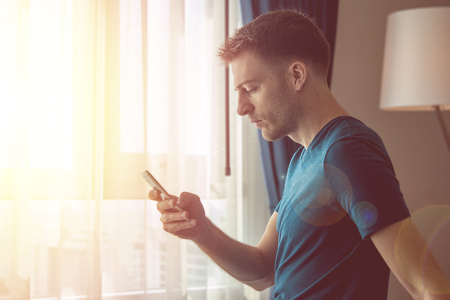 Young man keeping communication and close contact on mobile device with ...
