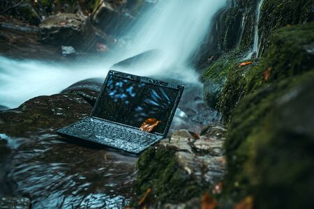 Laptop under the surface of the water on nature background. Testing ...