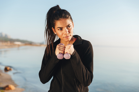 Calm sports woman doing fitness exercise with dumbbells while looking ...