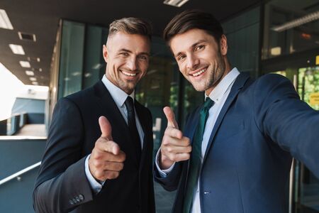 Photo of beautiful two businessmen dressed in formal suit showing ...