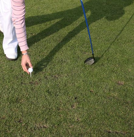 Young golfer placing the ball on a tee peg before his shot - Stock ...
