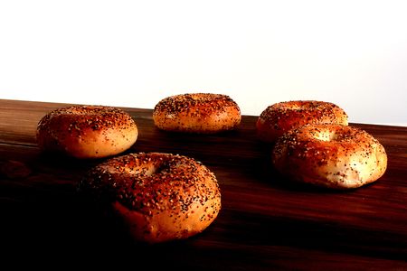 Five rolls strewed by a poppy and sesame on a wooden table with a white ...