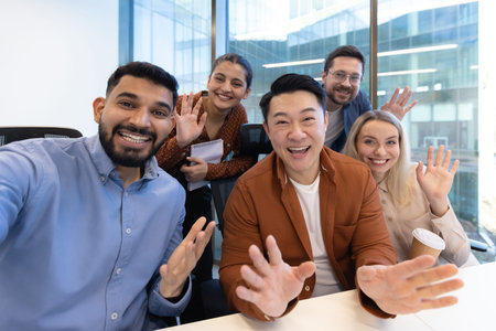 A diverse group of colleagues wave enthusiastically at the camera ...