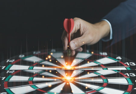Businessman holding a red dart aiming precisely at the center of the ...