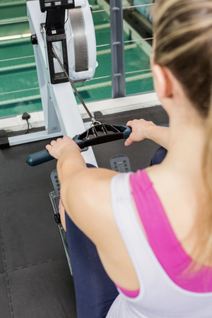 Woman exercising on rowing machine at gym - Stock Image - Everypixel