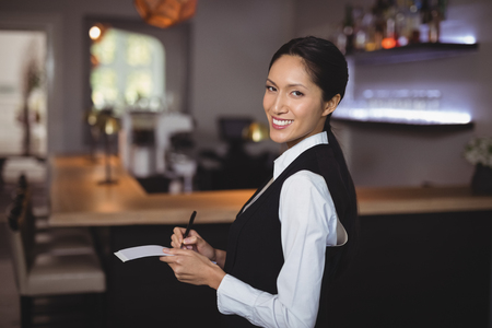 Smiling waitress writing order on notepad in restaurant - Stock Image ...