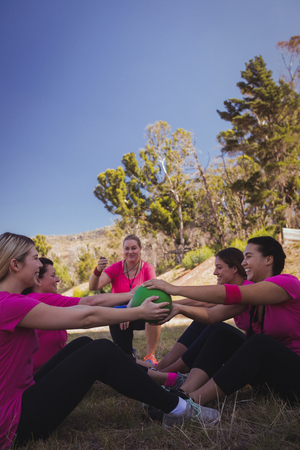 Female trainer instructing women while exercising in the boot camp on a ...