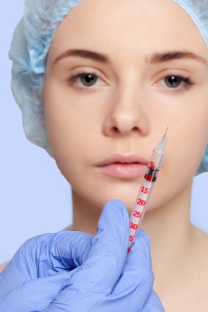 Attractive young woman gets cosmetic injection. Doctors hands making an ...