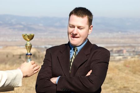 brunette European businessman squinnies at golden cupの写真素材 [40004660542 ...