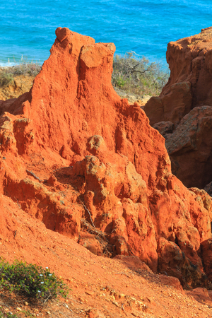 Summer evening Atlantic ocean shore with red clayey earth and heart ...