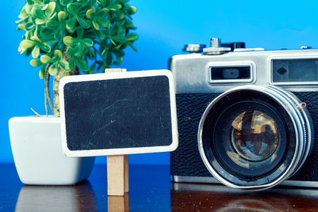 wooden signage, vintage camera and artificial plant on wooden desk with ...