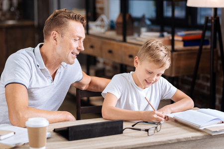 Smiling father watching his son make notes - Stock Image - Everypixel