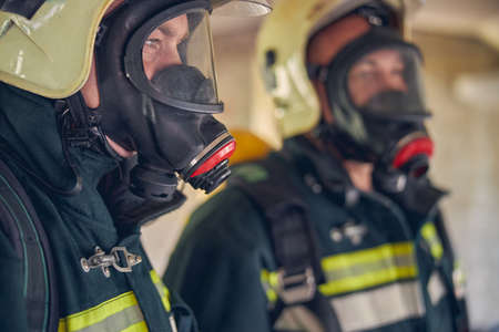 Close up portrait of firefighters in green fireproof uniform listening ...