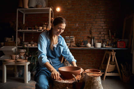 Beautiful Caucasian craft woman modeling ceramic bowl in modern pottery ...
