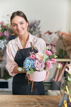 Professional florist young woman is doing bouquets at flower shop ...