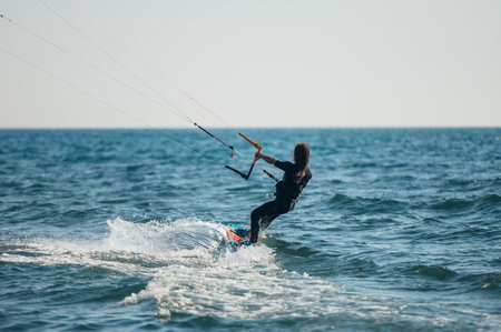 Young sporty woman on a kiteboard kitesurfing on the clear waves of the ...